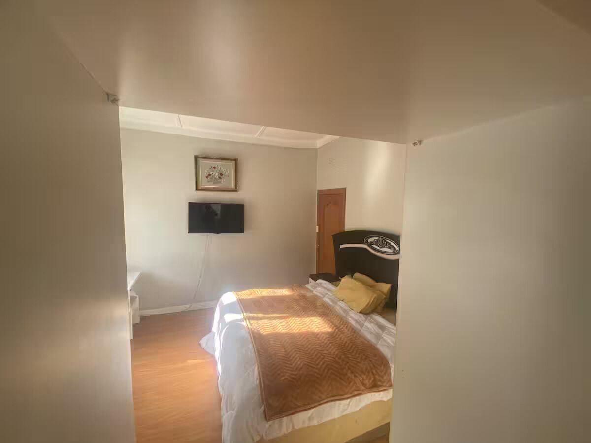 Um quarto com uma cama, uma televisão na parede e uma porta.