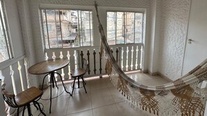 Quarto com rede, mesa e duas cadeiras.
