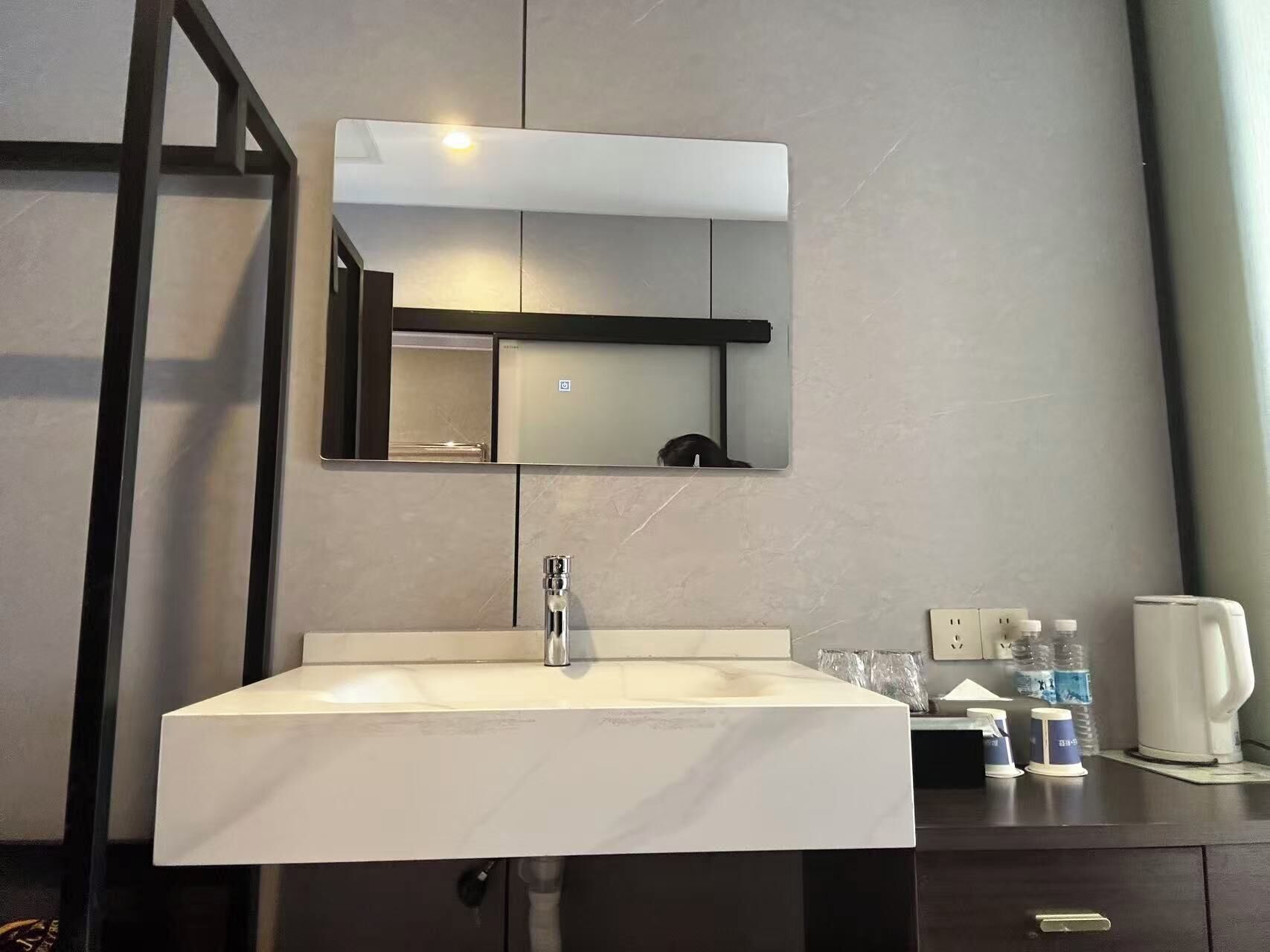 Uma casa de banho moderna com uma pia branca, um espelho, um porta-toalhas e uma máquina de café.