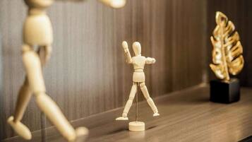 Um manequim de madeira numa prateleira com um objeto decorativo dourado.
