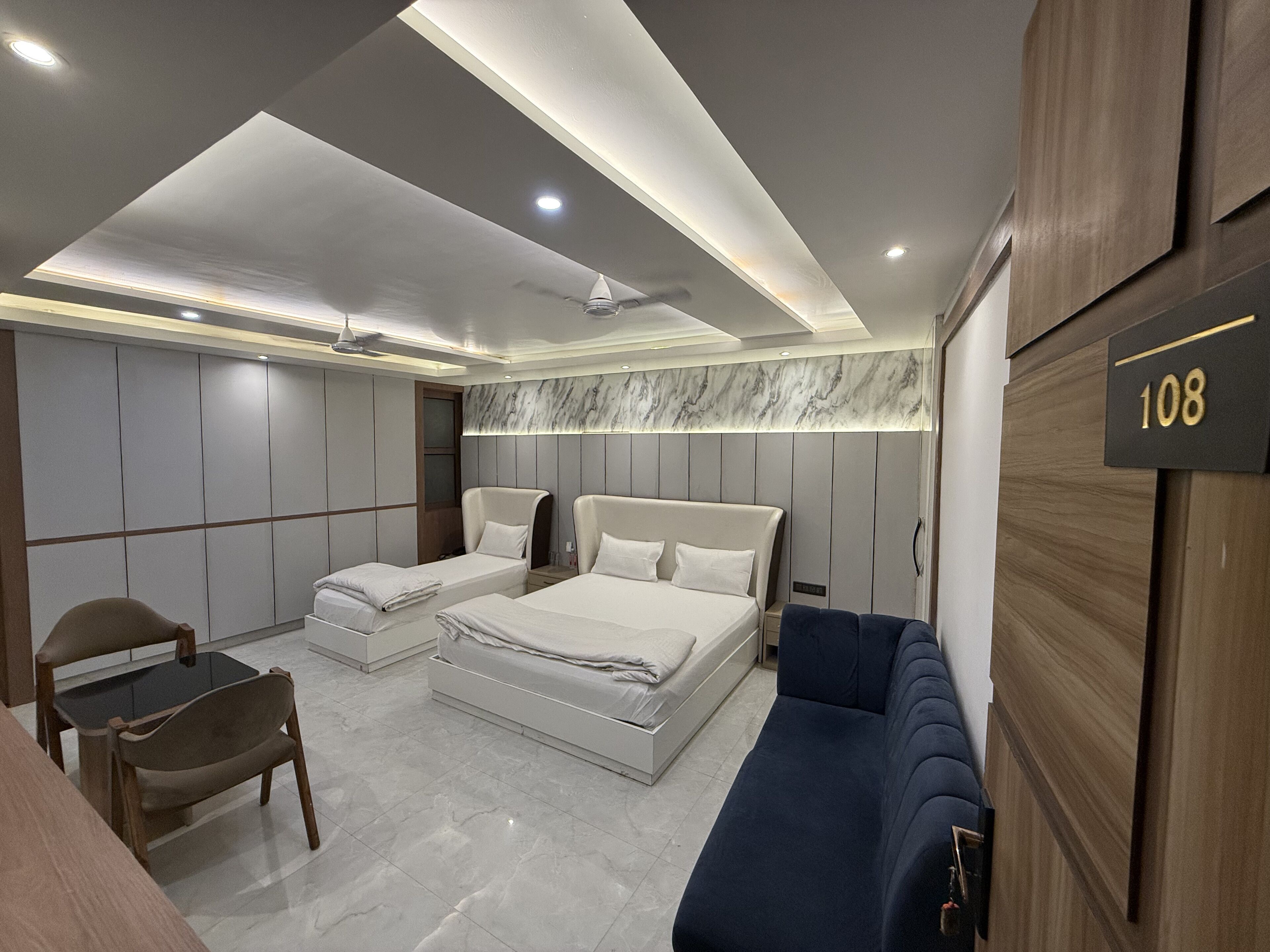 Quarto moderno com duas camas, um sofá, uma escrivaninha e um ventilador de teto.
