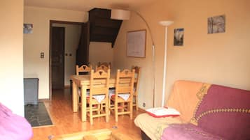 Uma sala de estar acolhedora com uma mesa de jantar de madeira e cadeiras, um sofá e um abajur.