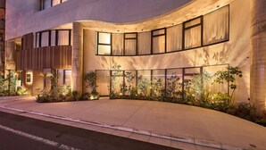 Um hotel moderno com fachada curva, grandes janelas e área de entrada bem iluminada com plantas.