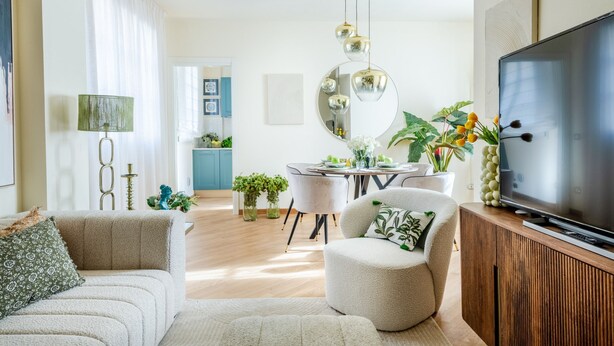 Uma sala de estar moderna com sofá, poltrona, televisão e área de jantar.
