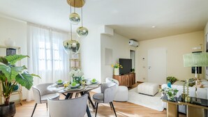 Uma sala de estar moderna com área de jantar, sofá, mesa de centro e televisão.