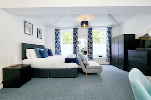 Quarto com cama, mesa de cabeceira, cômoda e vista para o exterior.