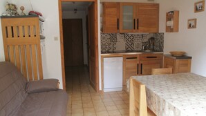 Um espaço compacto com cozinha compacta, área de refeições e sofá.