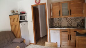 Uma cozinha compacta com armários de madeira, micro-ondas, lava-louças e uma área de jantar com mesa e cadeiras.