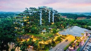 Um hotel imponente com vários andares, cercado por vegetação exuberante e um corpo d'água.