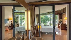 Quarto de hotel moderno com uma grande porta de vidro deslizante para uma varanda, uma cama, uma escrivaninha, uma cadeira e um banheiro com uma pia espaçosa.