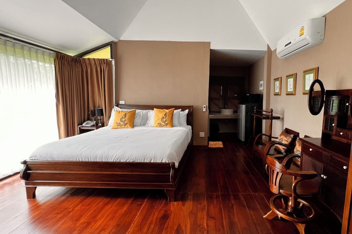 Quarto de hotel com cama grande, móveis de madeira, escrivaninha e guarda-roupa.