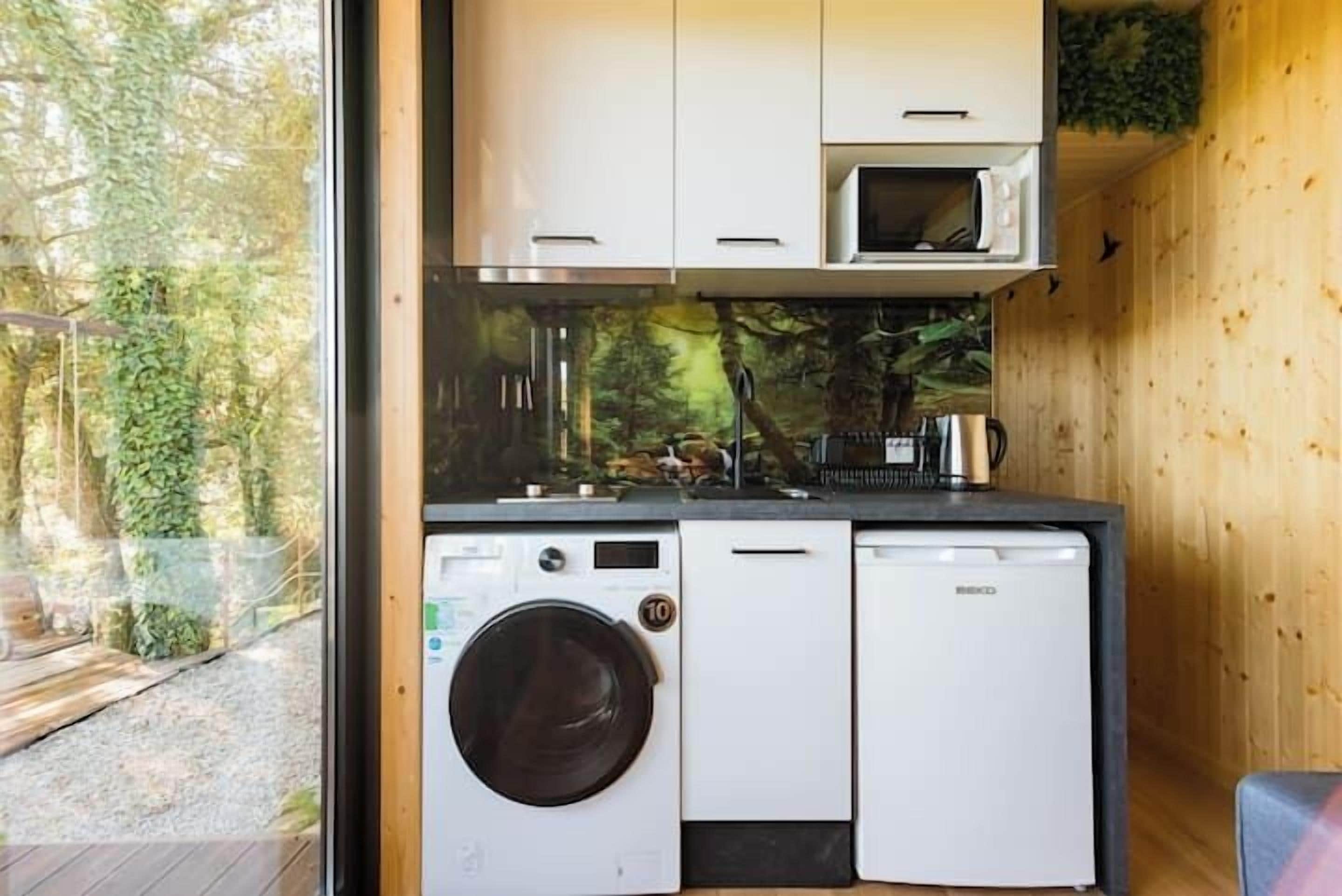 Cozinha compacta com máquina de lavar, lava-louças e micro-ondas.