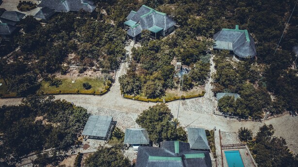 Vista aérea de uma área residencial com várias casas, uma piscina e um jardim bem cuidado.