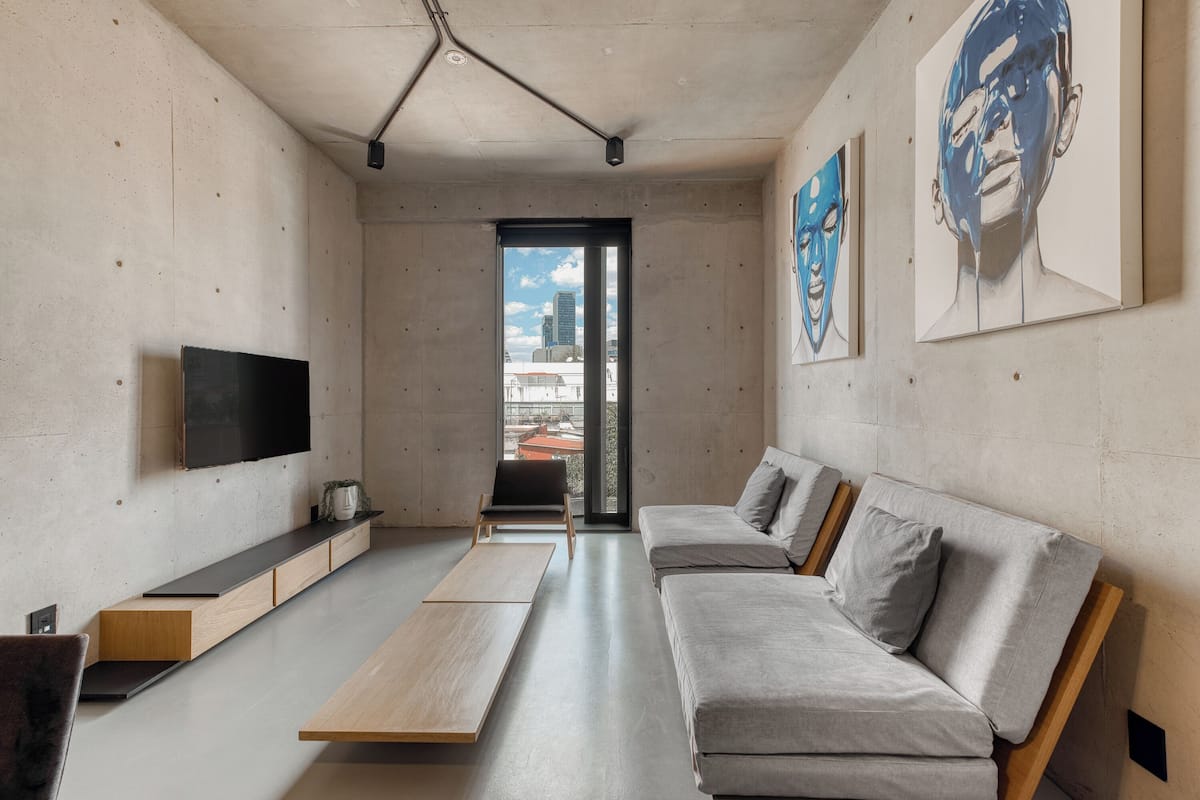 Uma sala de estar moderna com um sofá, uma televisão e obras de arte nas paredes.
