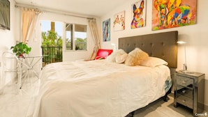 Quarto moderno com uma cama grande, mesa de cabeceira, cadeira e varanda com vista.
