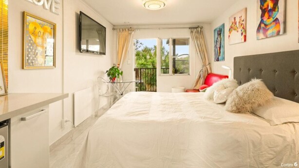 Quarto com uma cama grande, TV na parede e obras de arte.