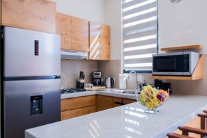 Apartamento Deluxe, 1 quarto | Cozinha privada | Um frigorífico/congelador grande, um micro-ondas, uma placa de cozinha 