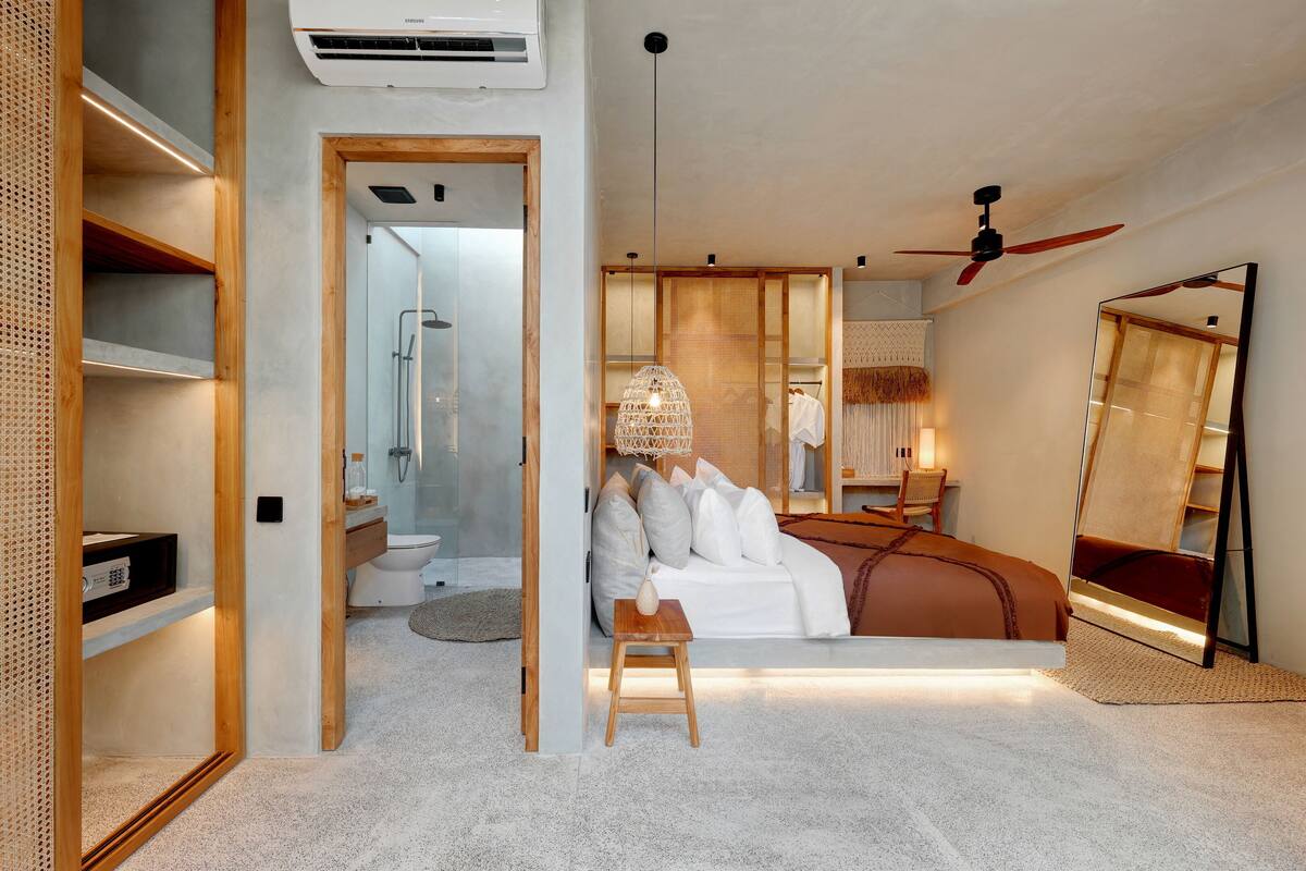 Quarto moderno com cama, mesa de cabeceira e um espelho grande.