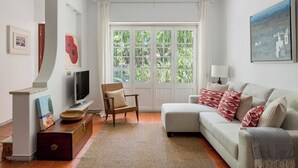 Sala de estar com sofá, TV e obras de arte na parede.
