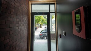 Porta que dá para área externa, com parede de tijolos de um lado e porta com painel de vidro.