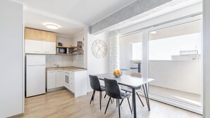 Uma cozinha moderna com armários brancos, micro-ondas e um espaço de jantar com mesa e cadeiras.