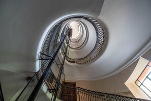 Uma escadaria em espiral com grades metálicas elaboradas e um pilar central.