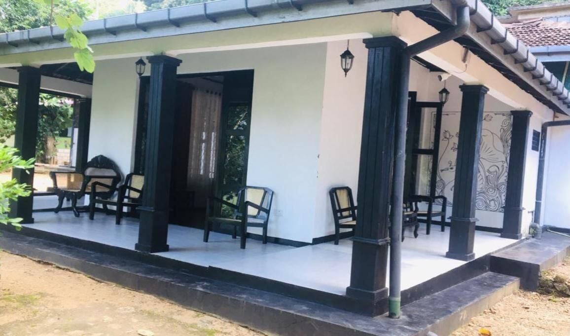Varanda coberta com colunas pretas e cadeiras.