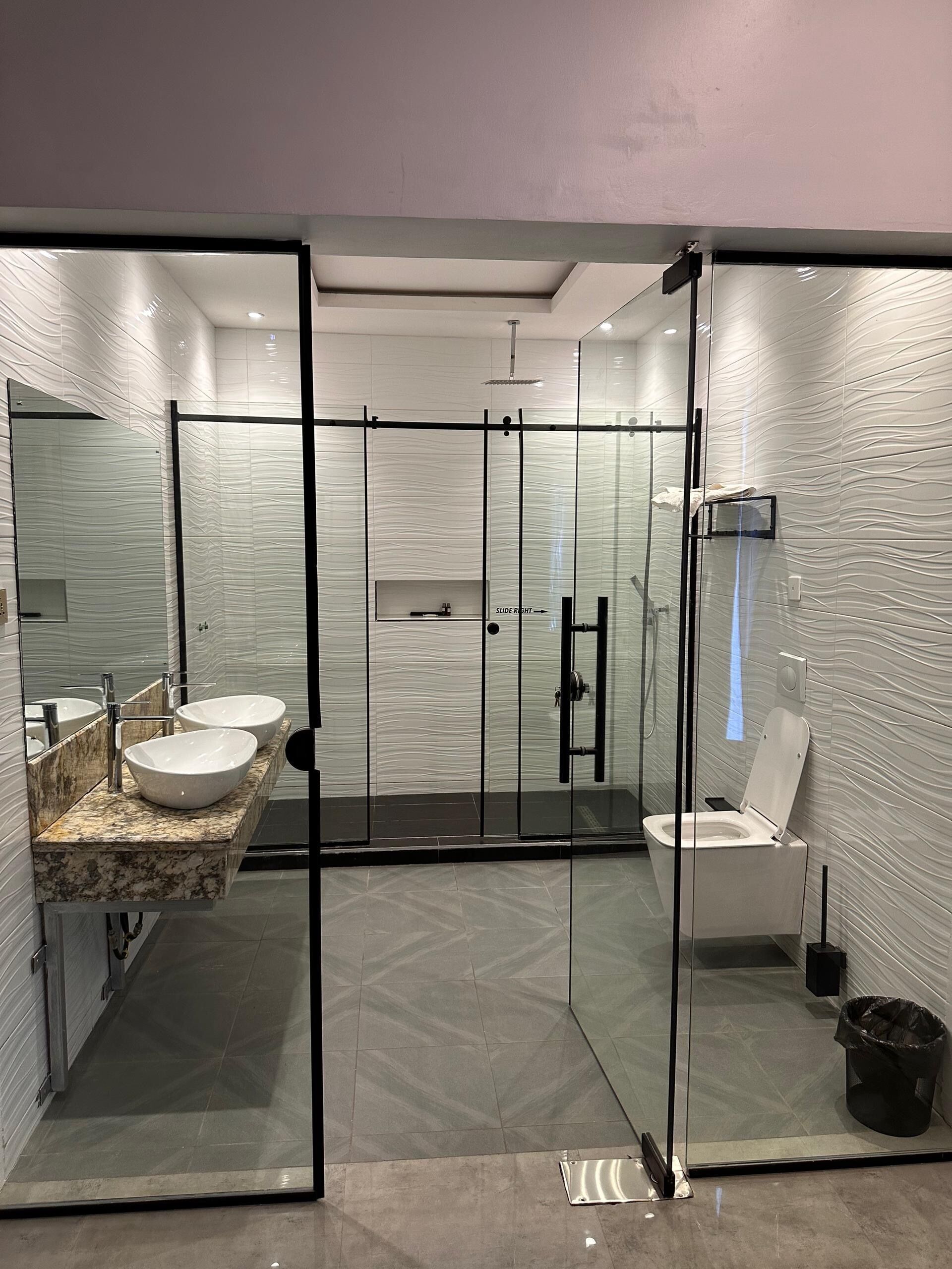 Uma casa de banho moderna com chuveiro em cabine de vidro, sanita e lavatório com bancada de mármore.