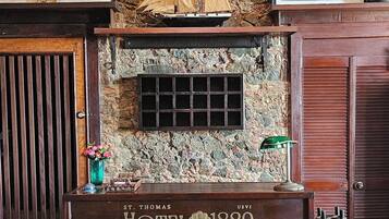 Balcão de recepção antigo com a inscrição 'St. Thomas Hotel 1829', com um painel de parede de pedra, quadros emoldurados e um modelo de navio.