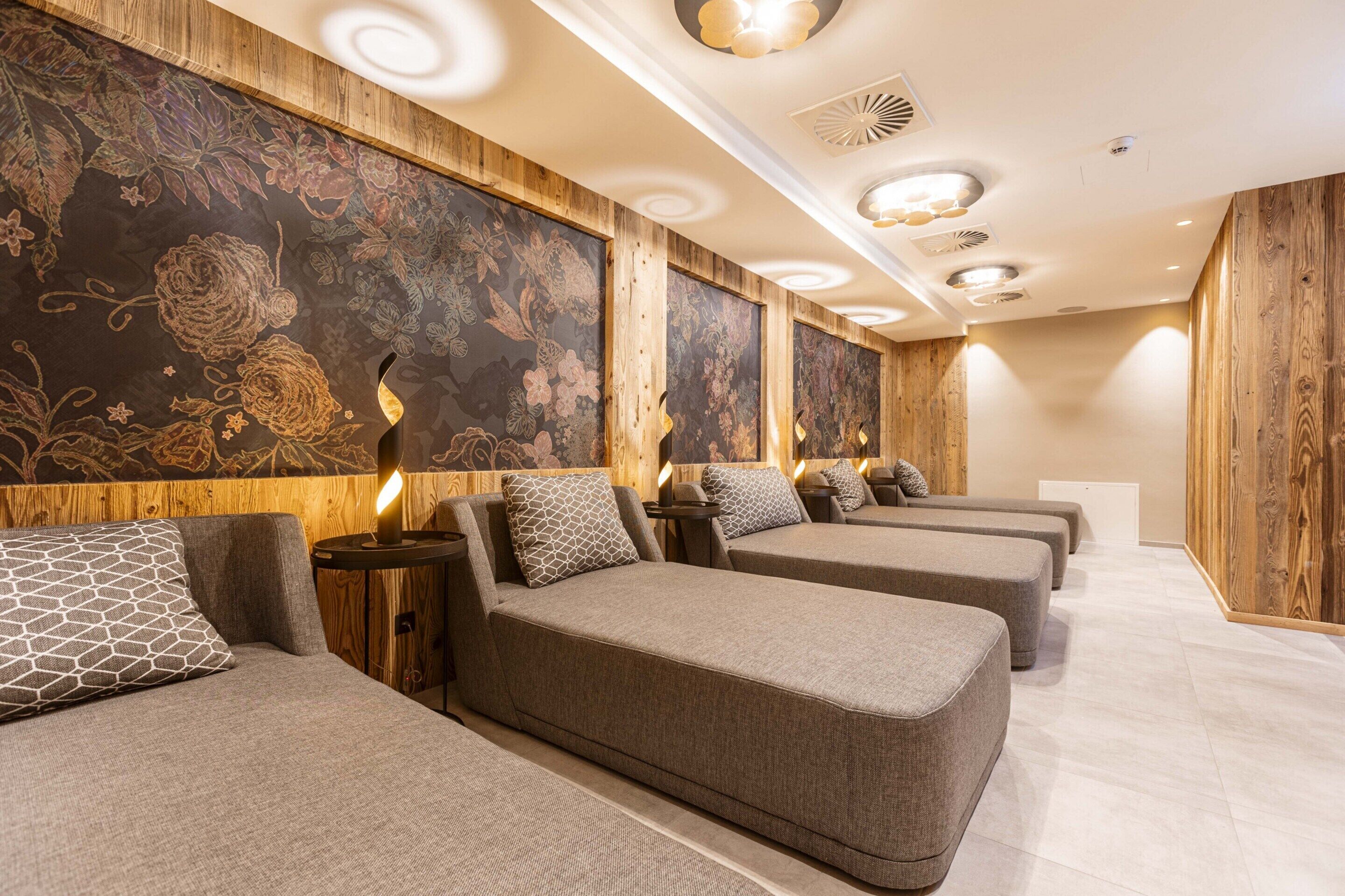 Um salão de spa com várias macas de massagem, painéis de madeira e um grande mural floral na parede.