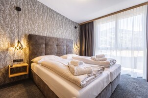 Quarto de hotel moderno com uma cama grande, uma mesinha de cabeceira e uma luminária fixada na parede.