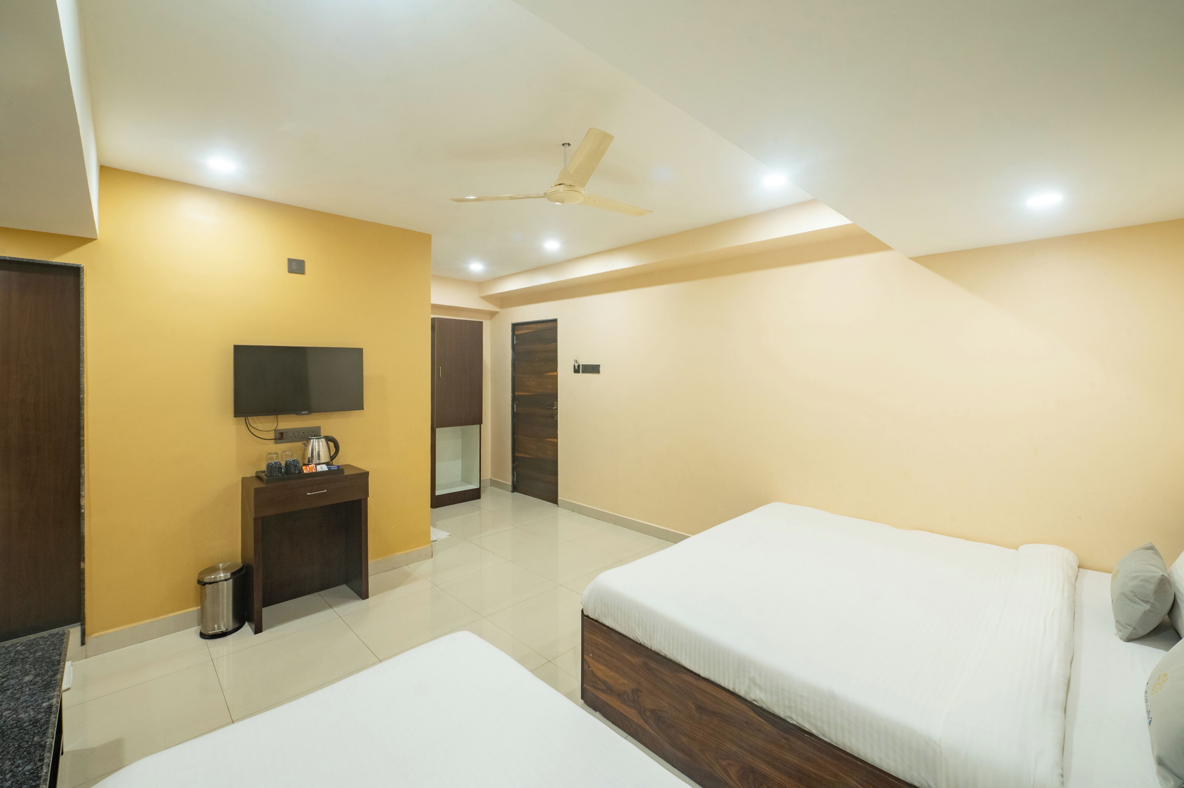 Quarto de hotel com cama, mesa de cabeceira, televisão e ventoinha no teto.
