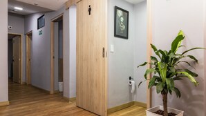 Um corredor com piso de madeira, um vaso de planta e um quadro na parede.