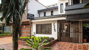 Entrada de hotel com uma placa indicando "HOTEL CASA 73 DELUXE", portão fechado e área de pátio com azulejos.