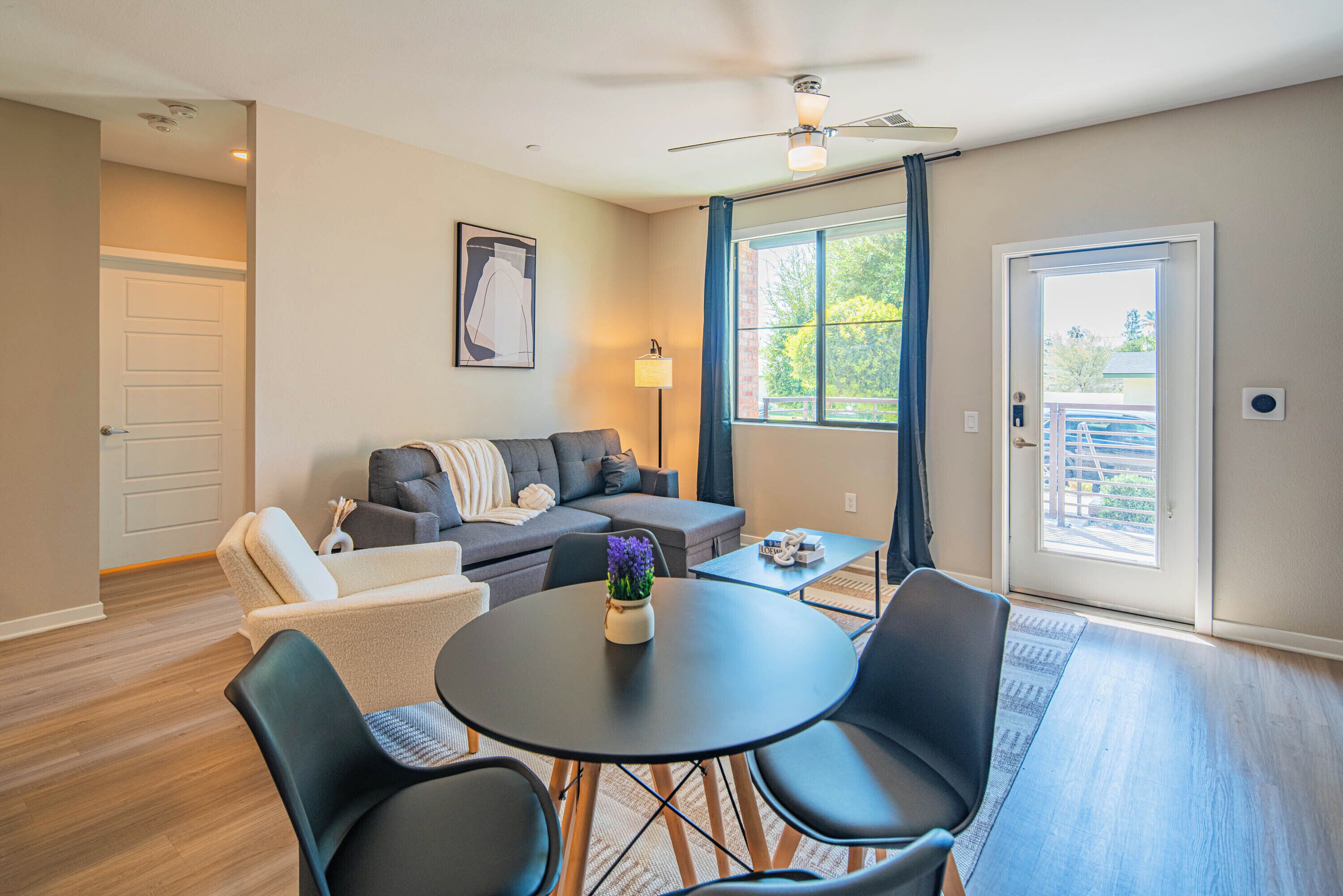Uma sala de estar moderna com sofá, cadeiras, mesa e ventilador de teto.