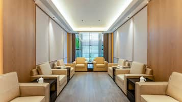 Um hall de hotel com área de estar central, uma janela grande e design moderno.