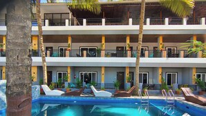 Um hotel com área de piscina, várias varandas e mobiliário de exterior.