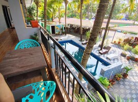Área da piscina com vista para a paisagem ao redor, incluindo palmeiras e um espaço de estar coberto.