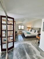 Quarto com uma cama grande, uma mesa de cabeceira, uma cadeira e uma janela.