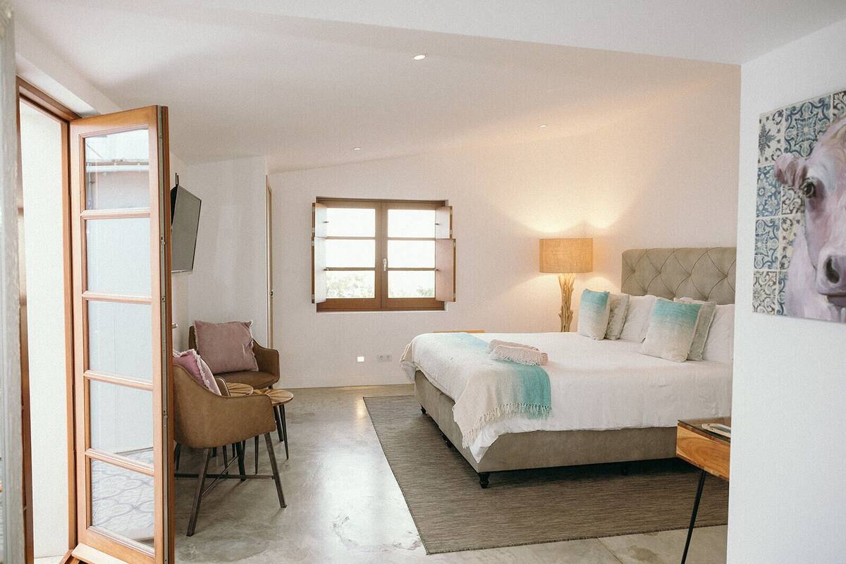 Quarto com cama, cadeira, escrivaninha, janela e luminária.