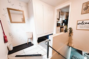Uma escadaria com corrimão, uma pequena mesa com um cesto e um letreiro de boas-vindas.