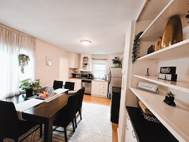 Cozinha moderna com armários brancos, área de jantar com mesa e cadeiras de madeira, e placa indicando que está fechada.
