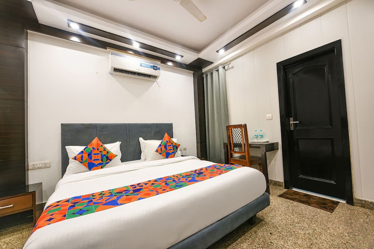 Quarto de hotel com uma cama, uma escrivaninha, ar condicionado e uma porta.