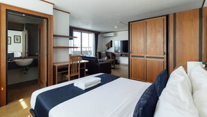 Quarto de hotel com uma cama grande, uma escrivaninha, uma cadeira, uma televisão e um guarda-roupa.