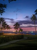 Na praia, areia branca, espreguiçadeiras, guarda-sóis 