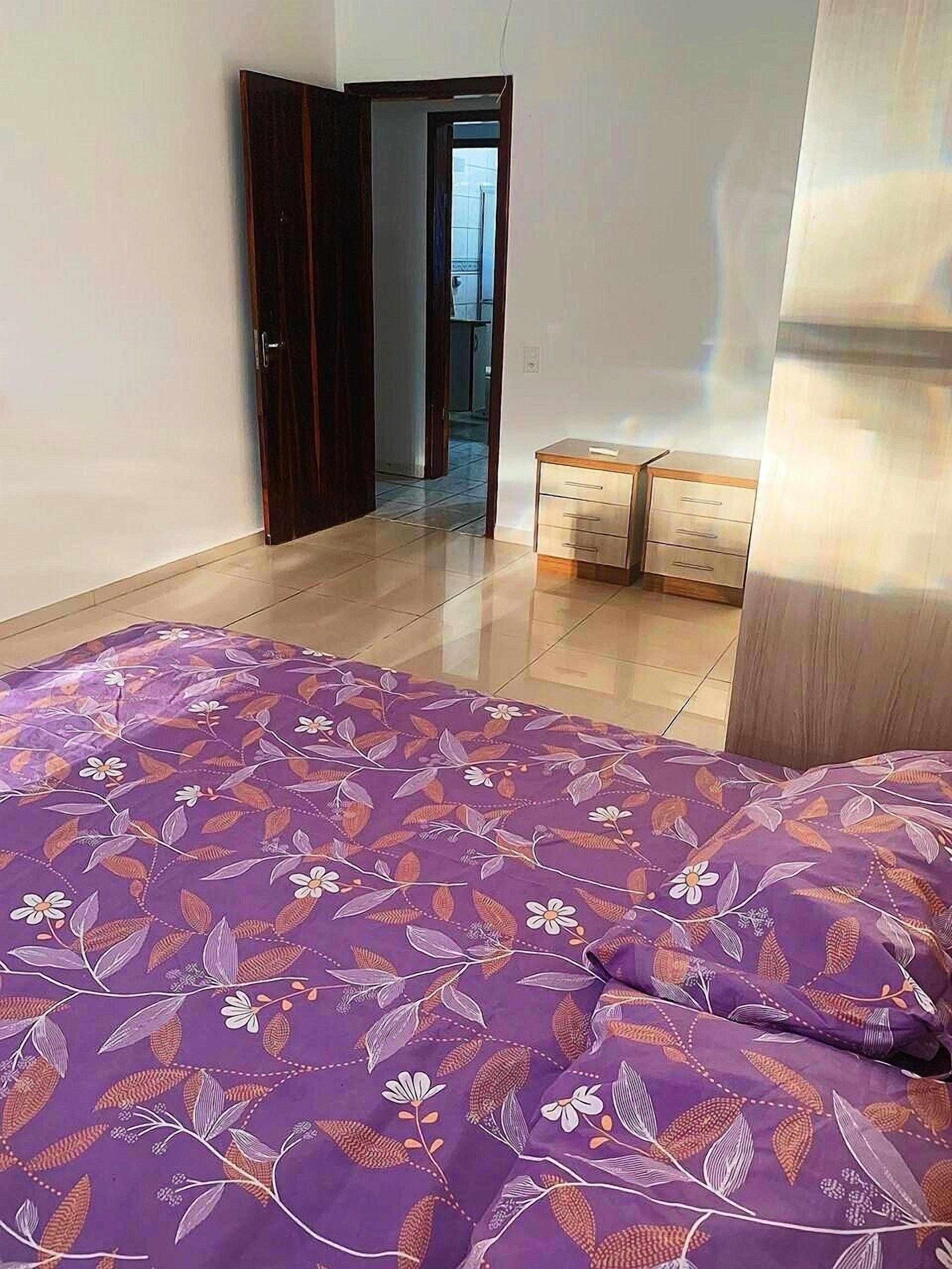Um quarto com uma cama, um guarda-roupa e uma pequena mesa de cabeceira.