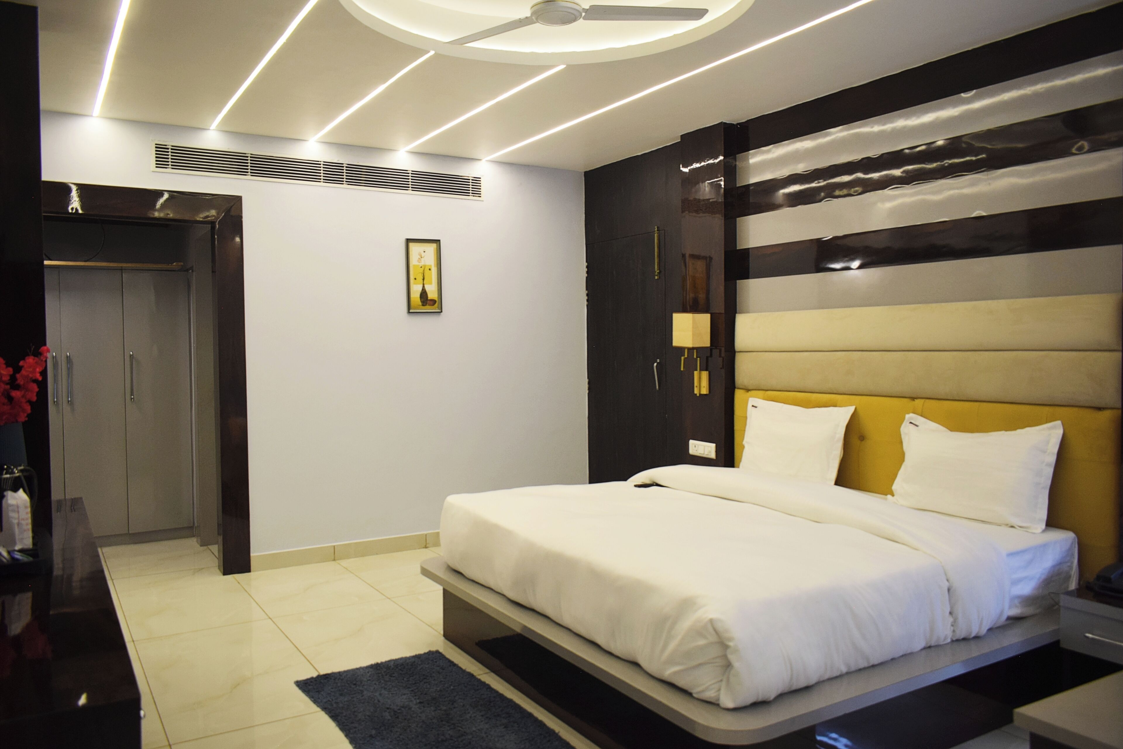 Quarto moderno com cama, mesas de cabeceira, ventoinha no teto e porta.