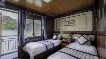Uma cabana com duas camas, teto de madeira, janela com cortinas e parede com quadros.