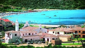 Uma vila costeira com praia, barcos e edifícios tradicionais.