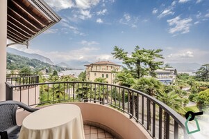 Varanda com mesa e cadeiras, com vista para área costeira, edifícios e montanhas.